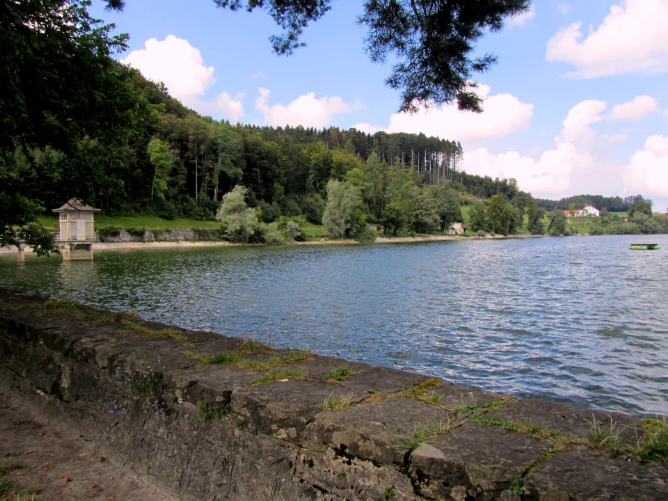 Lac de Bret entouré de forêts de pins, avec une petite maison au bord ...